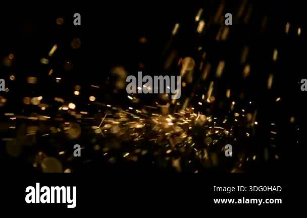 A dramatic shower of glowing orange sparks cascades down against a dark ...