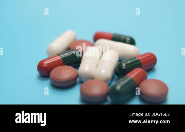 Assorted pills grouped on blue. Close-up video of assorted capsules and ...