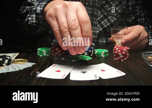 A man plays a poker game and throws blue chips onto playing cards with ...