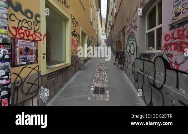 A narrow cobblestone alleyway features walls covered in colorful ...