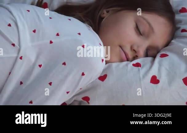 A 10-year-old girl sleeps sweetly in heart-shaped pajamas. High quality ...