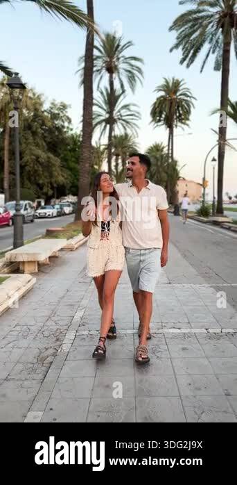 Happy young couple in love walking arm in arm on a promenade lined with ...
