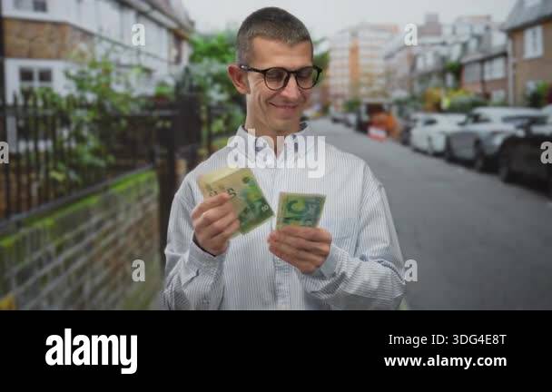Man smiling holding israeli shekel banknotes on an outdoor street with ...