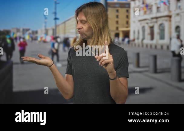 Man wearing a gray shirt presenting open palm while finger pointing ...
