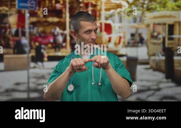 Man in green scrubs with stethoscope making heart gesture at outdoor ...
