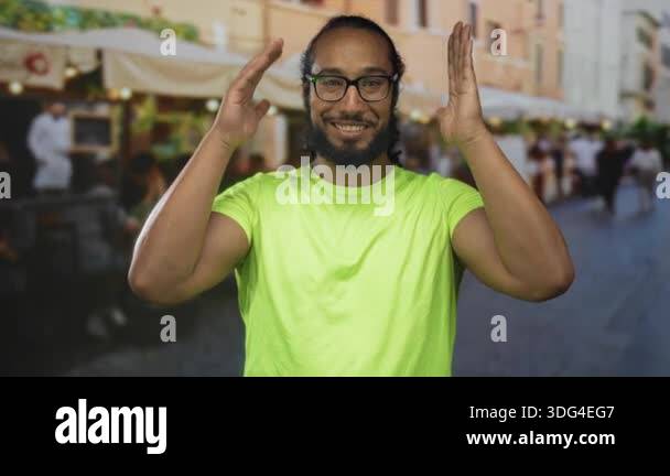 Man with hands framing face on a restaurant terrace smiling in a bright ...