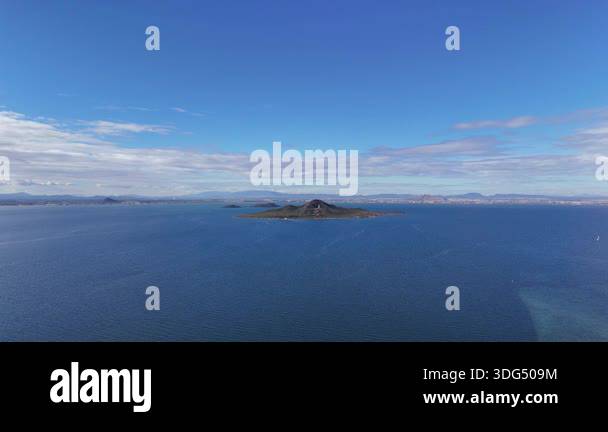 Wide panoramic view of a small island surrounded by calm blue sea with ...