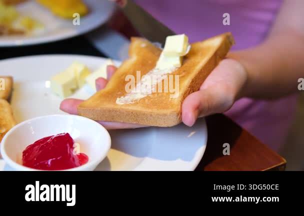 Spread redcurrant jam on a slice of toasted bread with butter using a ...