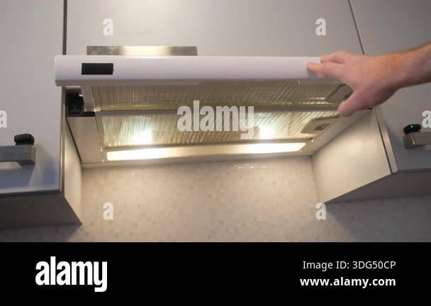 Close-up of a person lifting a stove extractor hood to turn on ...