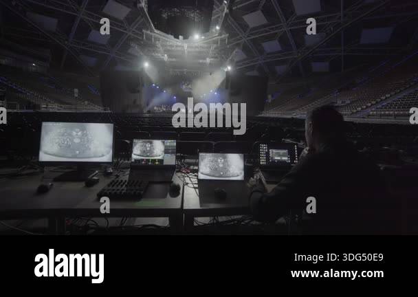 Light engineer monitors live feed from multiple screens in dark control ...