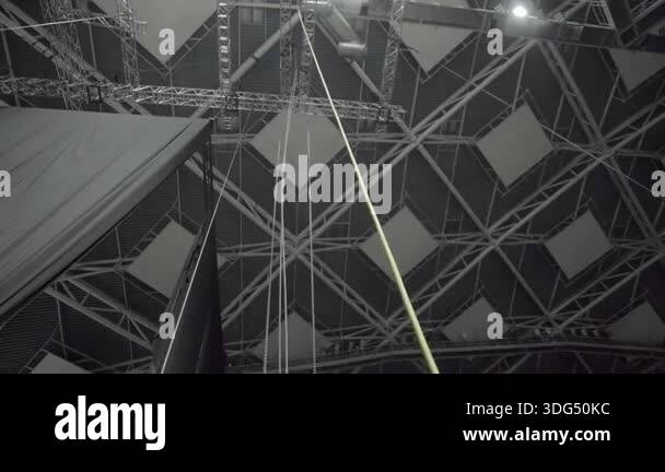 Overhead lights shine on ceiling rigging grid casting intense shadows ...