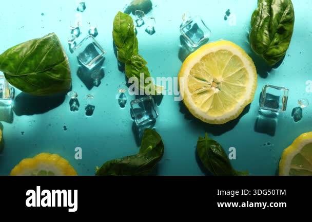 Lemon slices, fresh basil leaves, and ice cubes are artfully arranged ...