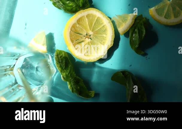 Lemon slices, fresh basil leaves, and ice cubes are artfully arranged ...