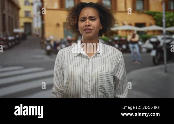 Woman in striped shirt showing palms up gesture and grimacing face at a ...