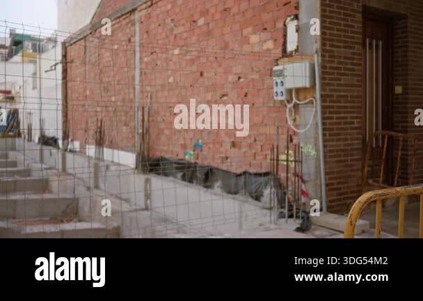 Construction site showing defocused brick wall, mesh fence and concrete ...