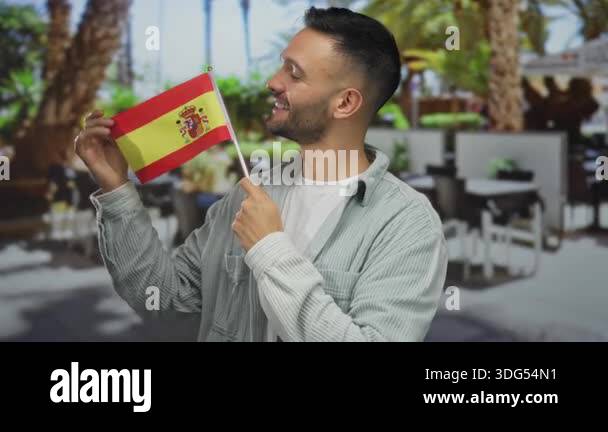Man holding spain flag smiling outdoors on terrace restaurant ...