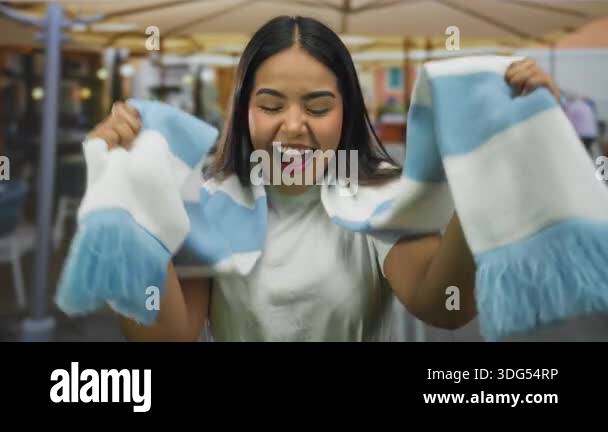 Woman lifts scarf while cheering at a restaurant with young latin ...