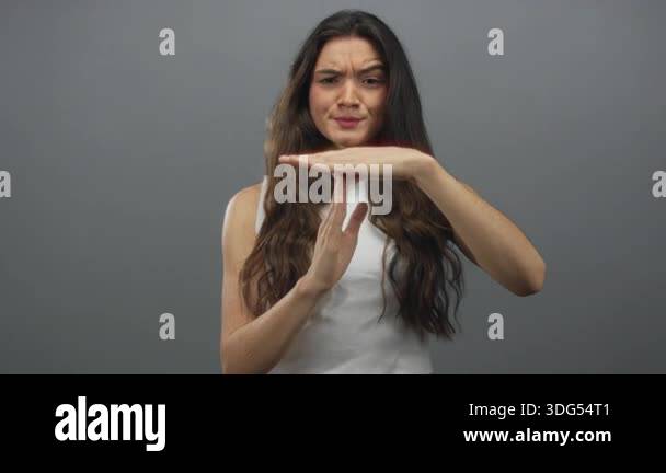 Woman with hands making timeout gesture and serious expression in grey ...