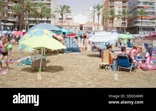 Beach scene with umbrellas, sand and palm silhouettes softly blurred in ...
