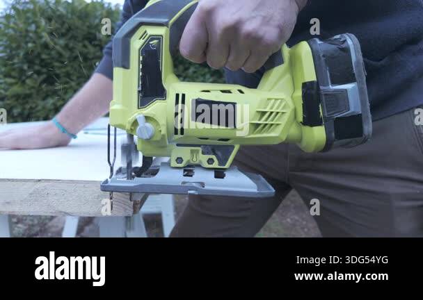 Side and rear angle showing cordless electric jigsaw cutting door while ...