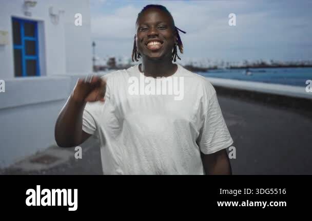 Man making ok sign with his hand at eye level on a seaside street near ...