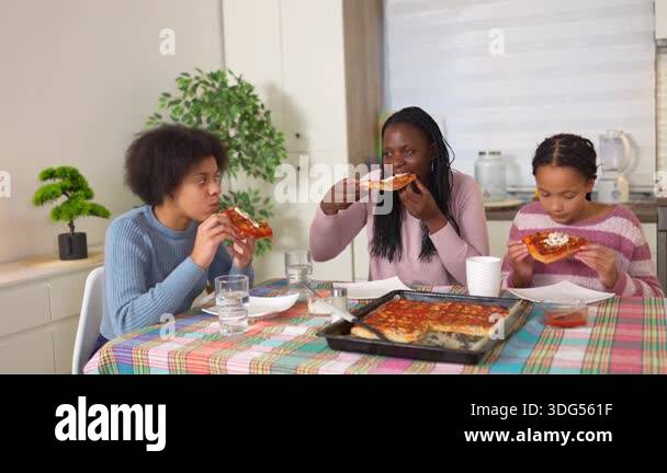Happy black family eating delicious homemade pizza for dinner together ...