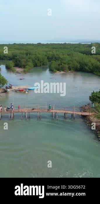 Majestic aerial view of a wooden bridge over a river meeting the sea in ...