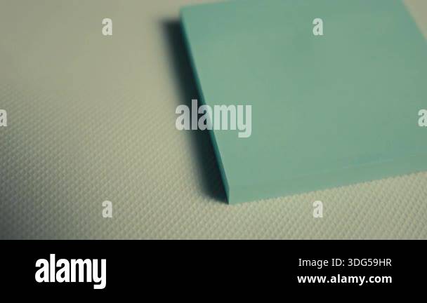 Minimal close-up of a blank blue sticky note on a white textured ...