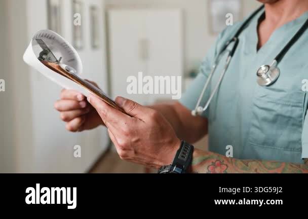 Medical professional in scrubs meticulously reviews and writes on a ...