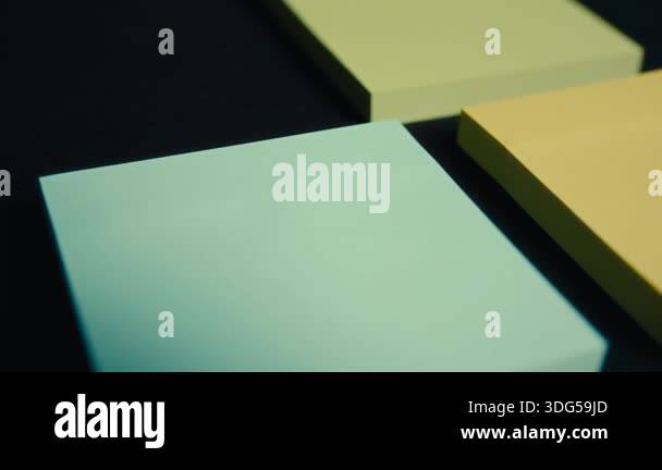 Close-up of pastel sticky note pads on a dark textured desk with ...