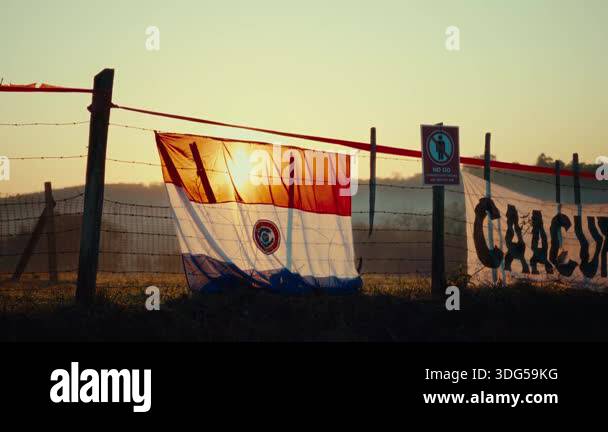 Paraguay national flag hanging on a wire fence at golden hour, backlit ...