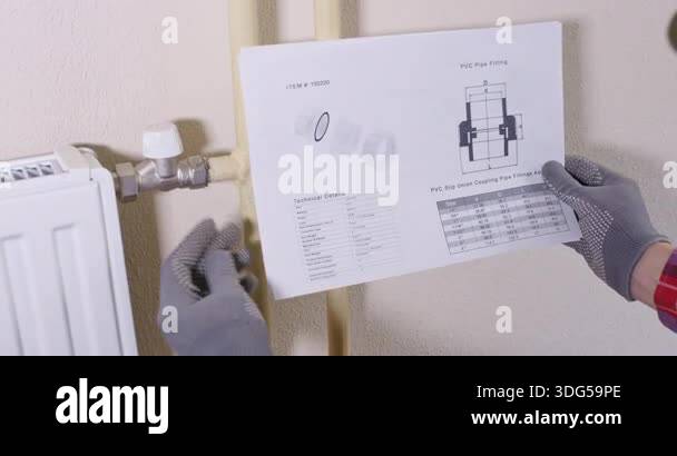 Gloved technician holds datasheet near light wall with radiator valves ...