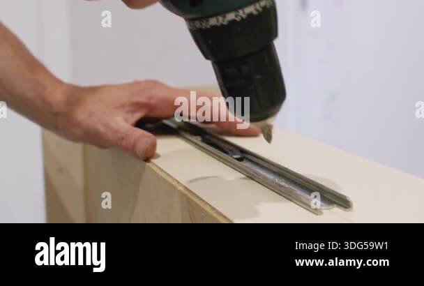 Electric screwdriver spins while screw exits metal rail smoothly under ...