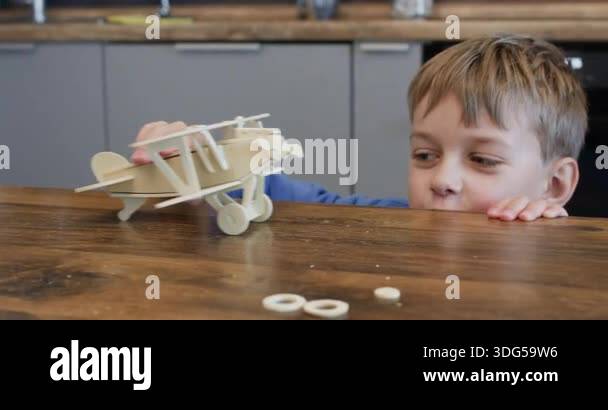Happy little schoolboy plays with plywood aeroplane model hiding behind ...