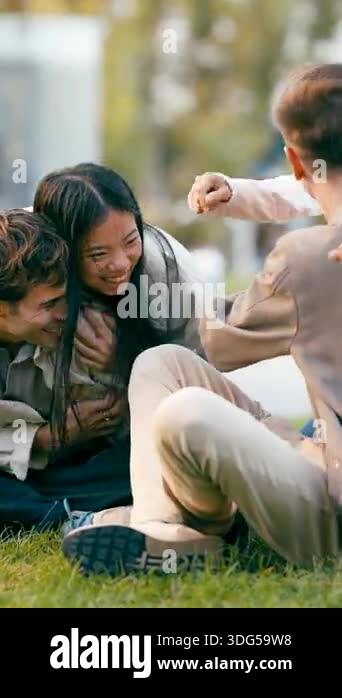 Diverse group of smiling young friends happily talking, hugging, and ...