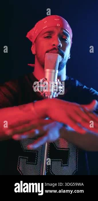 Young male artist with a bandana performing a hip hop song in a ...