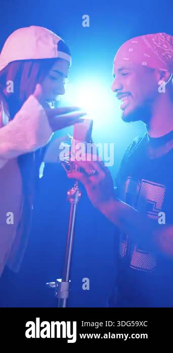 Energetic couple of hip hop singers performing a duet in a recording ...