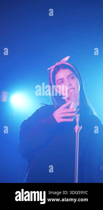 Young woman singing passionately into a professional microphone. An ...