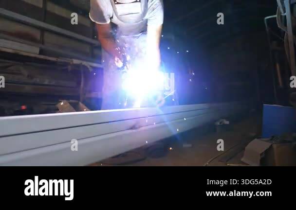 Manual laborer in protective mask welding iron detail at garage ...