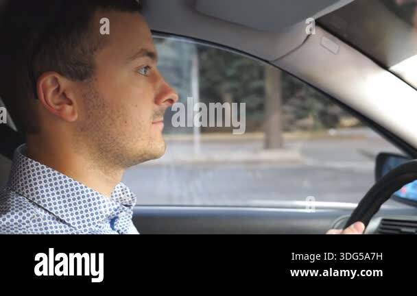 Young businessman with serious face driving automobile in downtown ...