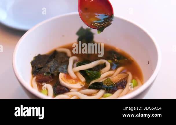 Close-up slow-motion shot of a person using chopsticks to pull thick ...