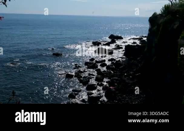 Moody aerial drone footage of waves breaking over dark volcanic rocks ...