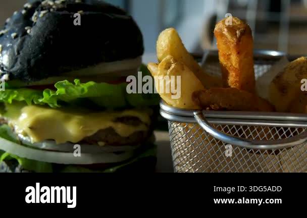 Red and blue light reflect off black table top with basket cheeseburger ...