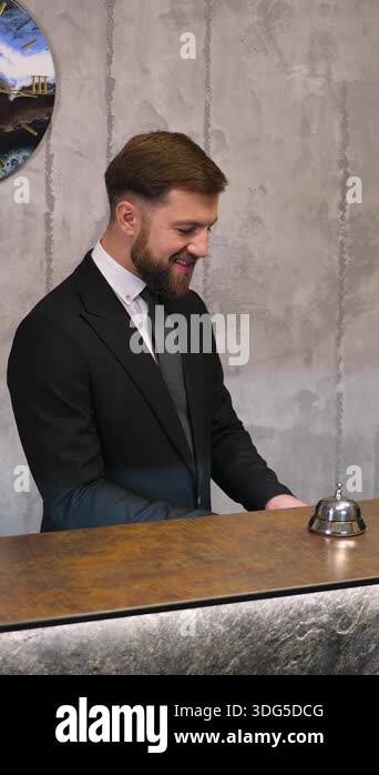 Friendly male concierge with a beard wearing a formal suit standing at ...