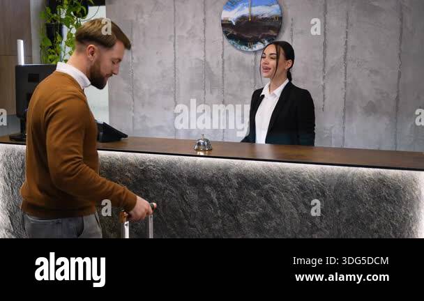 Friendly female receptionist assisting a male guest at the hotel front ...