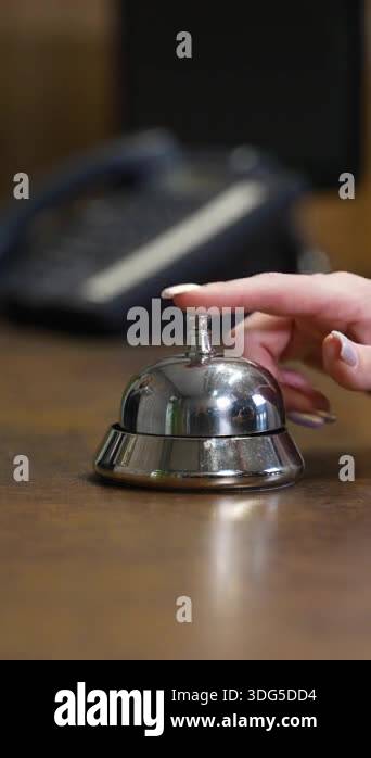 Female guests hand ringing a service bell at a hotel front desk. The ...