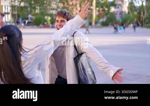 Slow motion of two happy friends hugging each other outdoors in a city ...