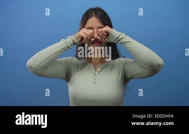 Young hispanic woman rubbing tired eyes in a bright studio while ...