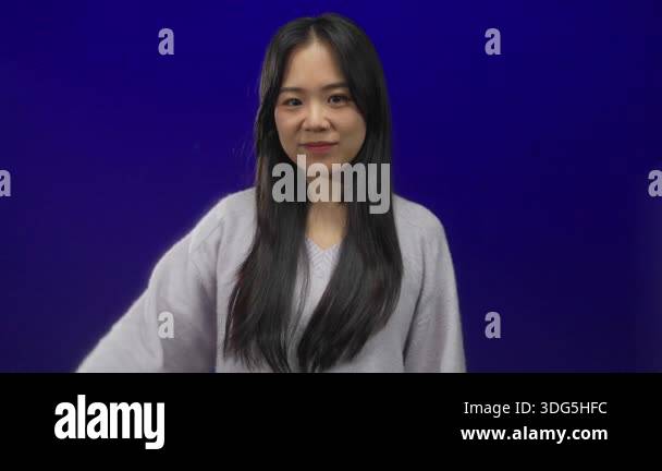 Young chinese woman gestures loser sign over isolated blue background ...