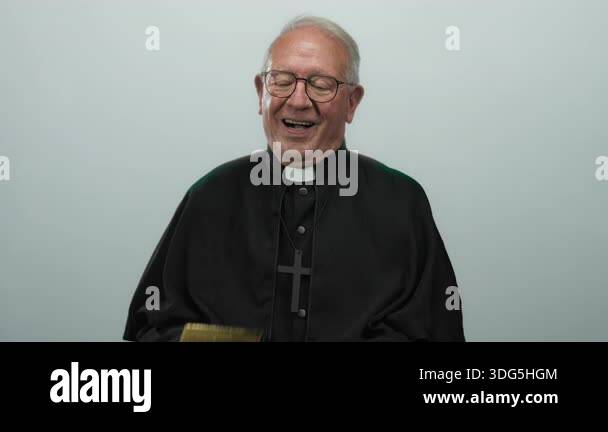 Senior priest passionately holding and kissing a closed bible against a ...